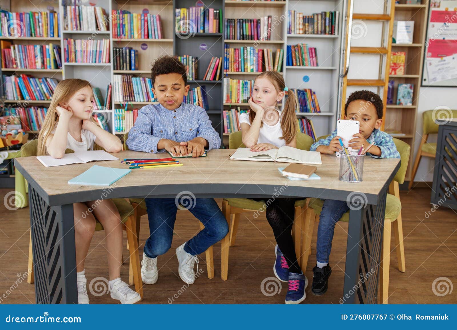 Multi-ethnic Pupils Study and Write at Table in Library or Classroom ...