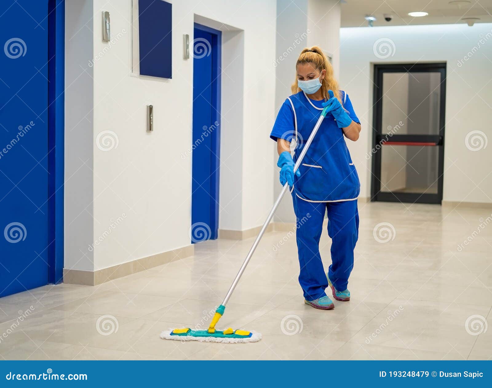 A Cleaning Lady with a Mask on Her Face Cleans the Hallway Stock Image ...