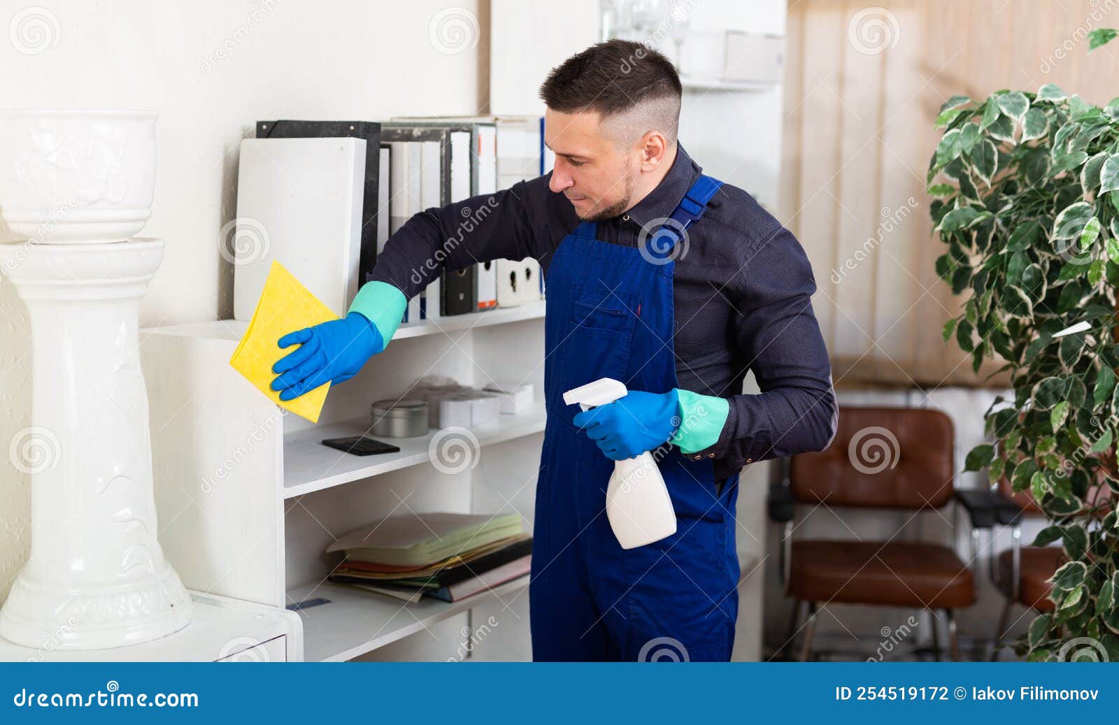 Cleaning Man in Overalls Wipes Dust from Table in Office Stock Photo ...
