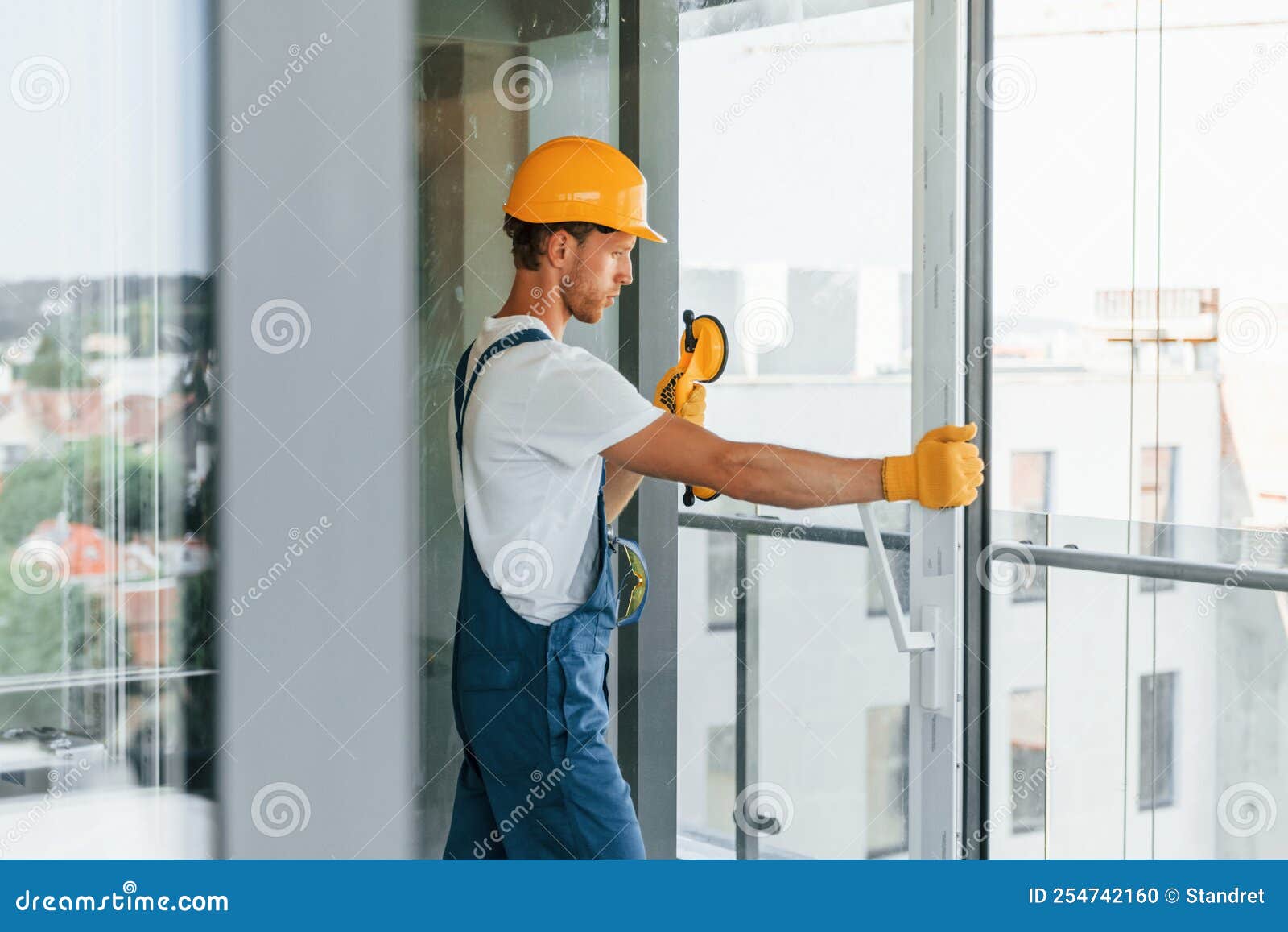 Clearing Windows. Young Man Working in Uniform at Construction at ... Clearing Windows. Young Man Working in Uniform at Construction at ...