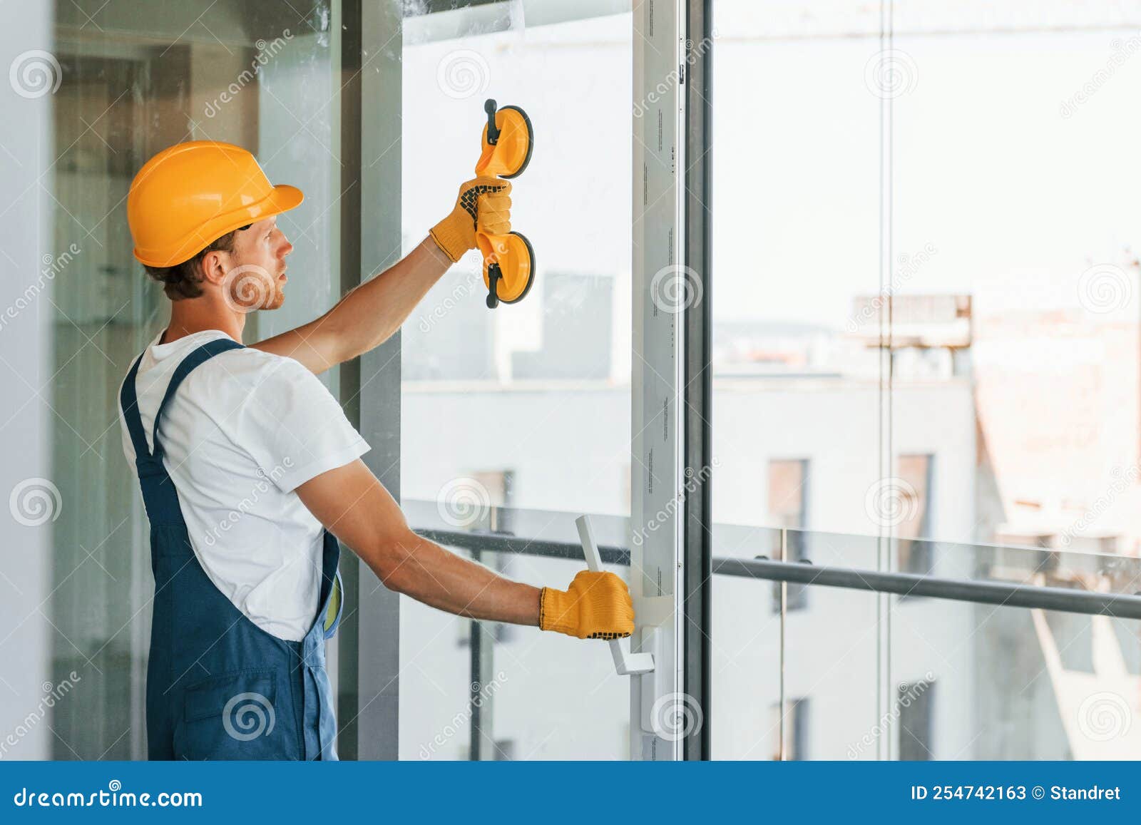 Clearing Windows. Young Man Working in Uniform at Construction at ... Clearing Windows. Young Man Working in Uniform at Construction at ...