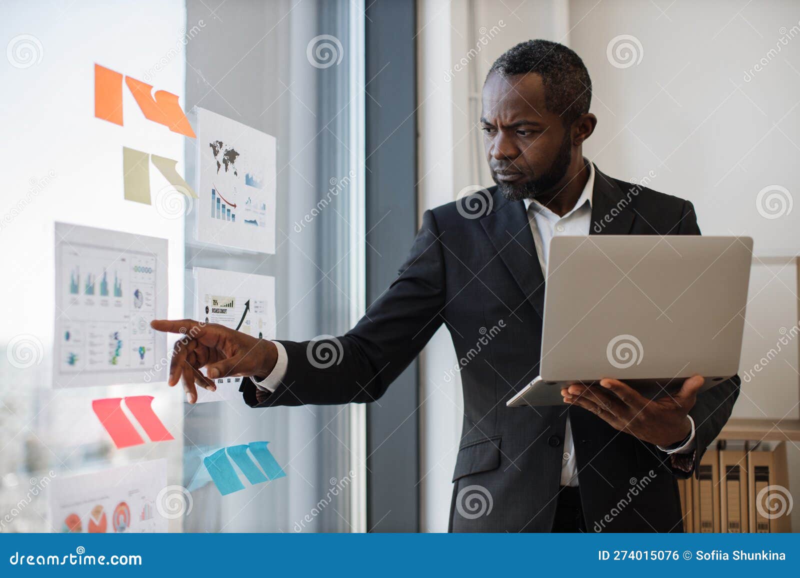 Clerk Examining Data on Computer and Diagrams on Board Stock Photo ...