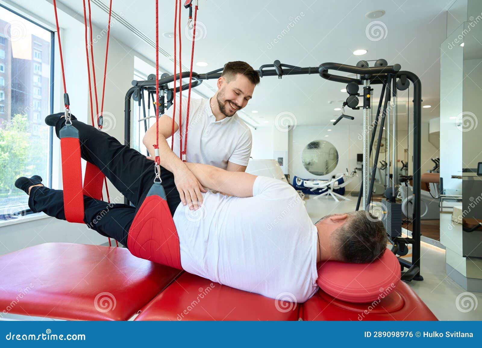 Man Doing Resistance Exercise with Assistance of His Personal Trainer ...