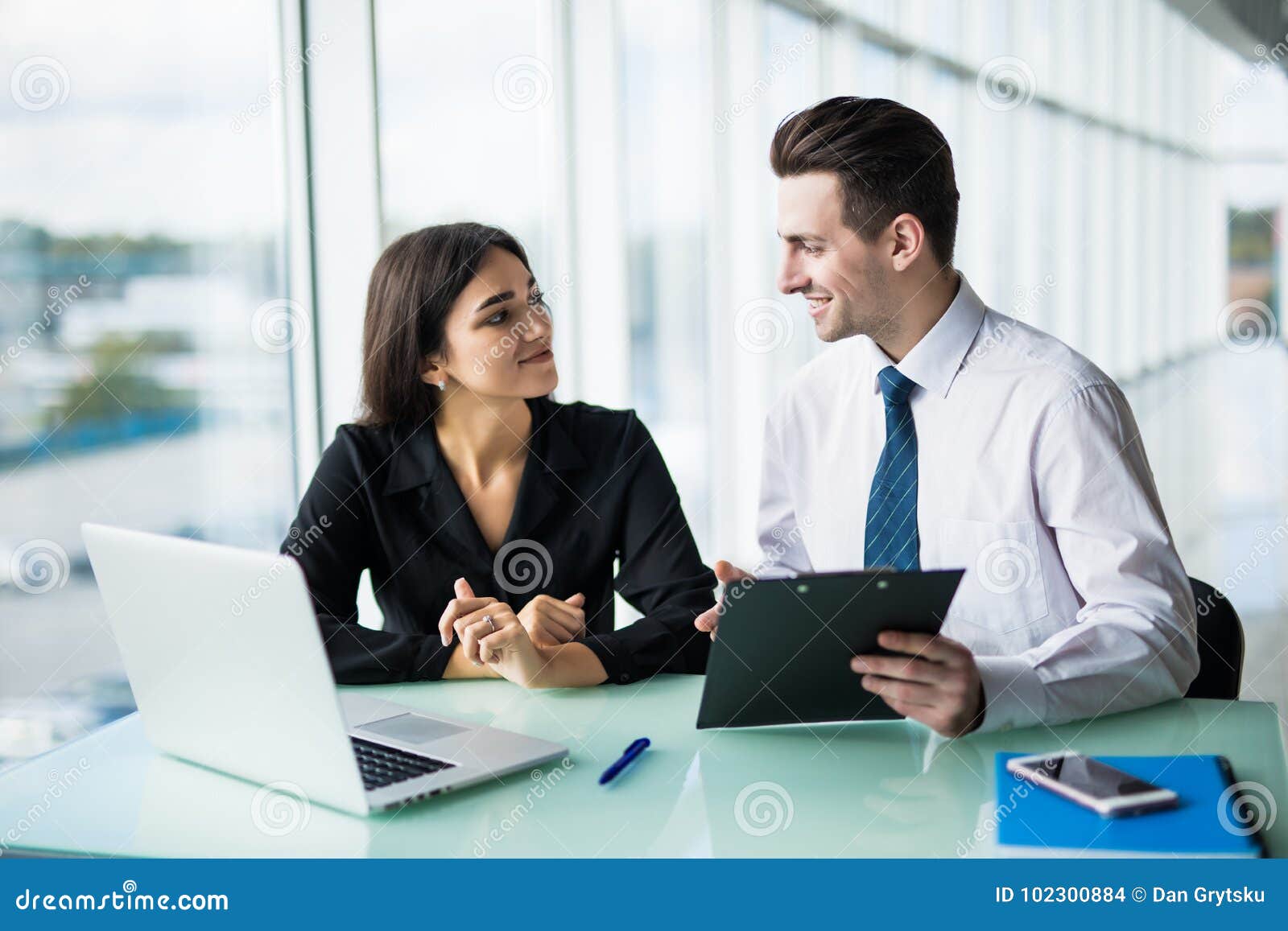 Client Signing a Document in an Office with a Businesswoman Looking the ...