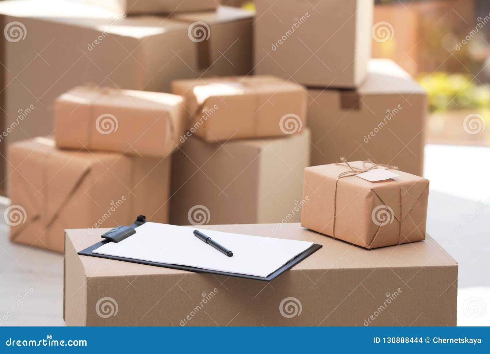 Clipboard, Parcel With Tag And Blurred Stacked Boxes On Background ...