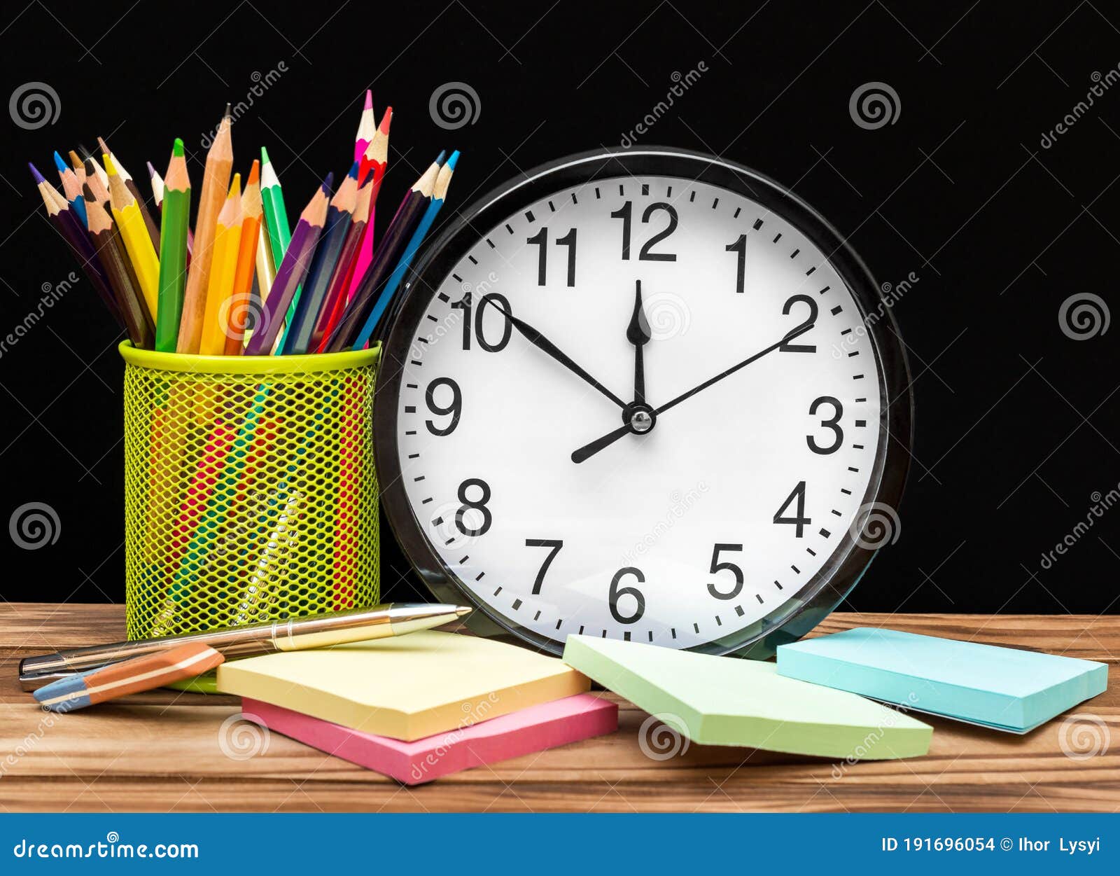Clock with Colored Pencils in Holder and Stickers the Table Against ...