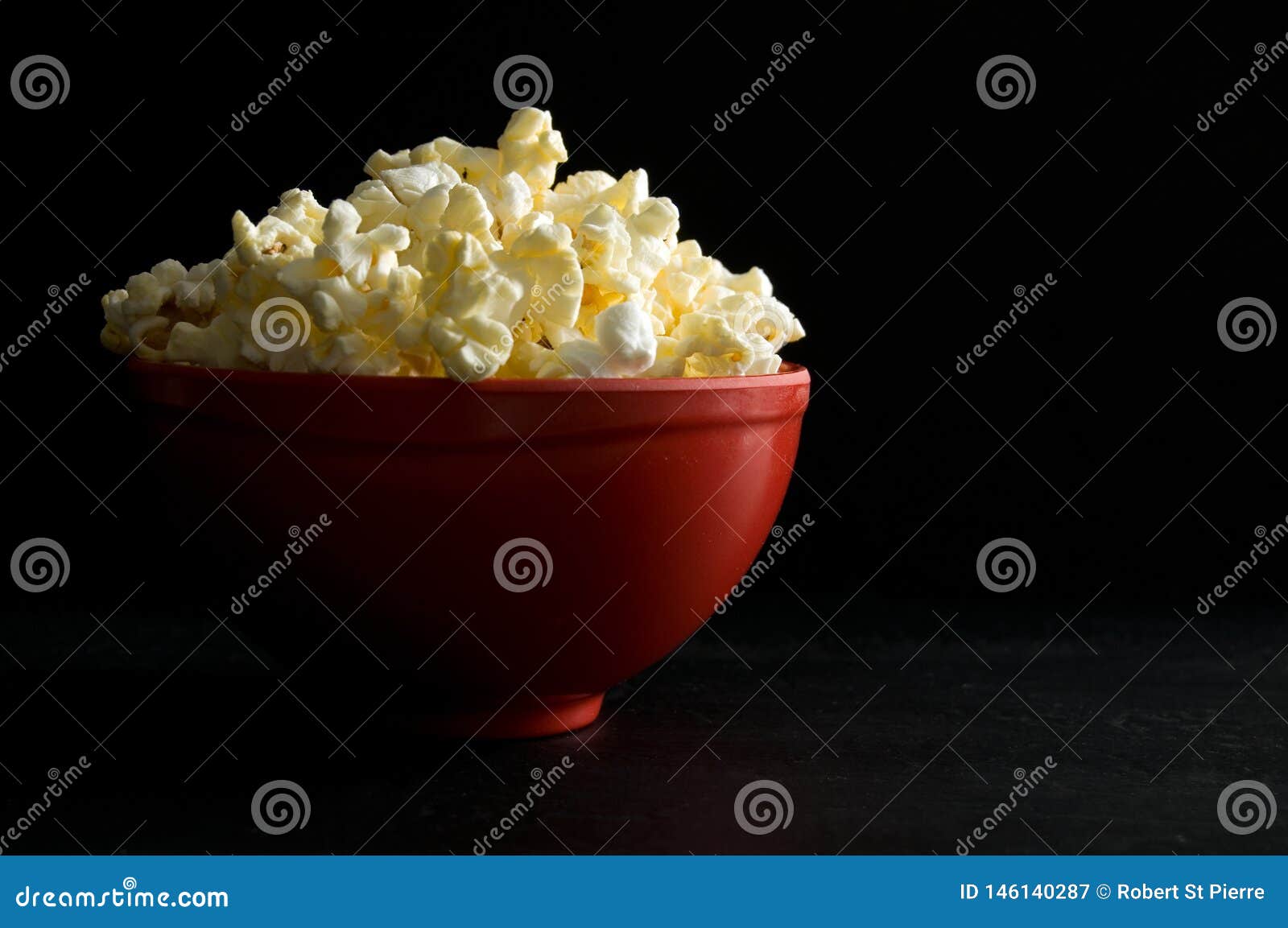 Close Side View of Buttered Popcorn in a Red Bowl Isolated on Black ...