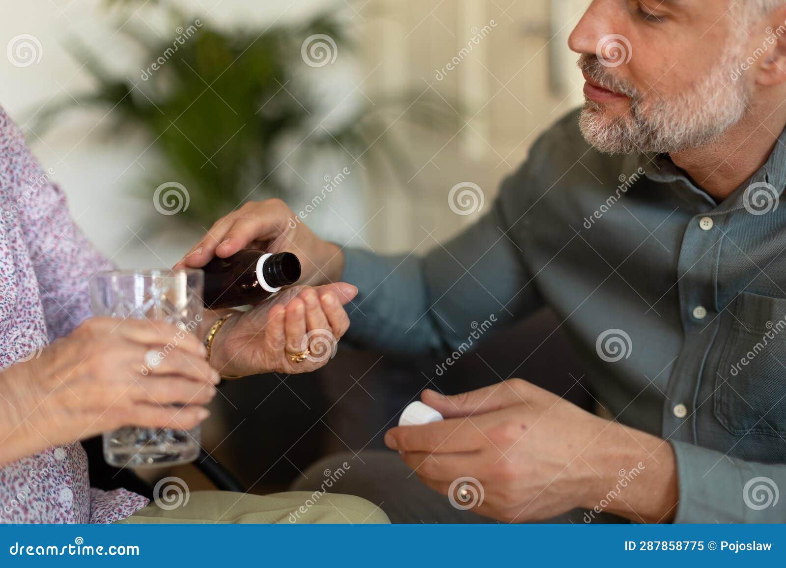 Adult Son Giving Pills To His Ill Mother Helping To Take Medication
