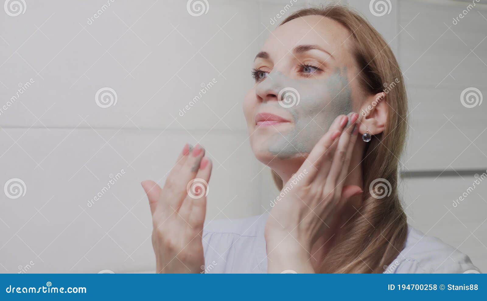 Close Up Of Adult Woman Applying Clay Mask On Her Face Looking In