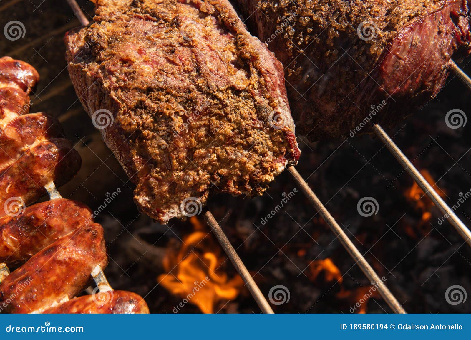 Close Up of Beef and Sausage Roasting on a Spit with Ember and Fire ...