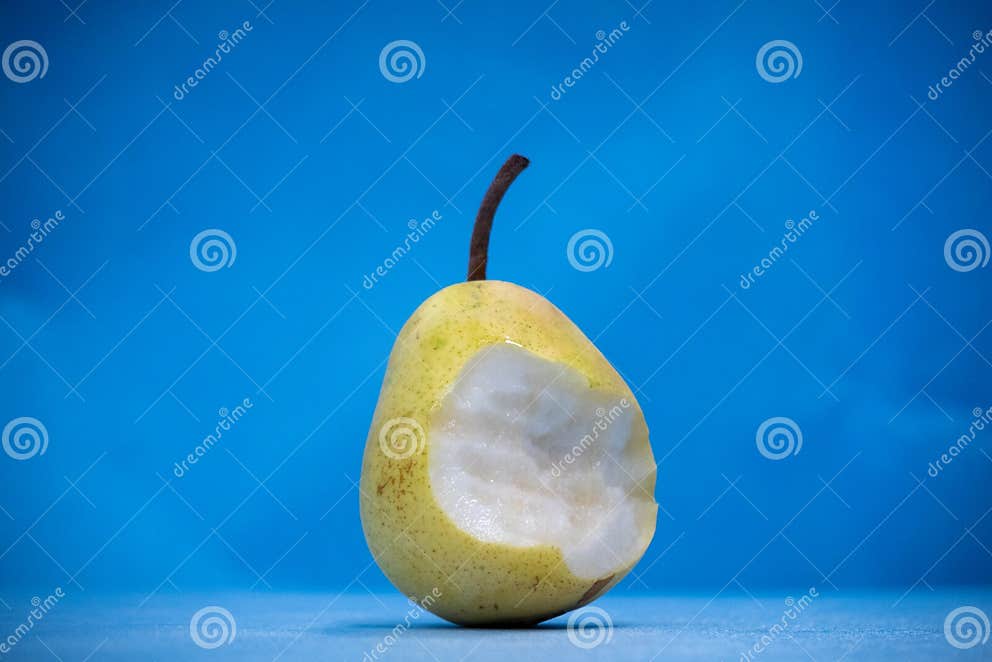 Close Up of a Bitten Pear is Standing and the Background is Blue Stock ...