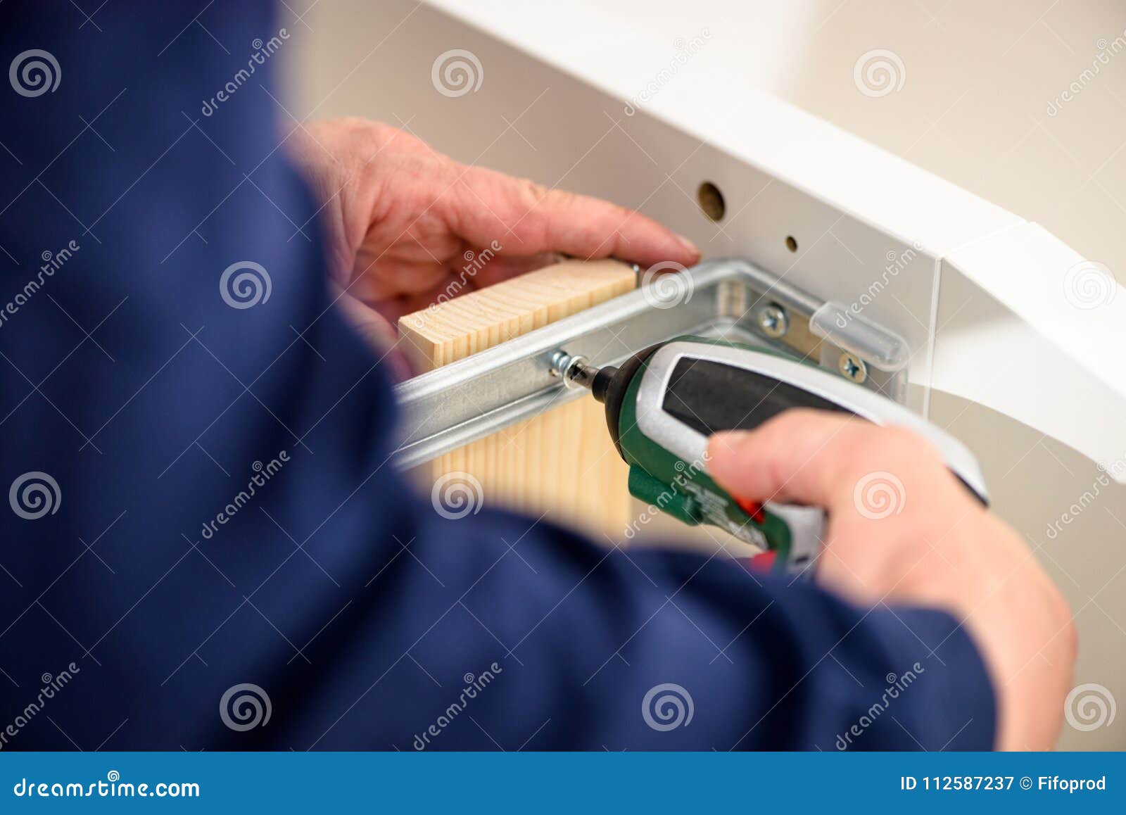 Close Up On Hands With Cordless Screwdriver Assembling Furniture Stock