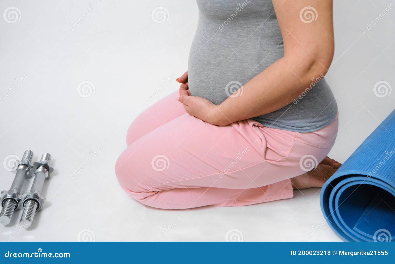 Close Up Of Caucasian Pregnant Woman Sitting On Her Knees On White