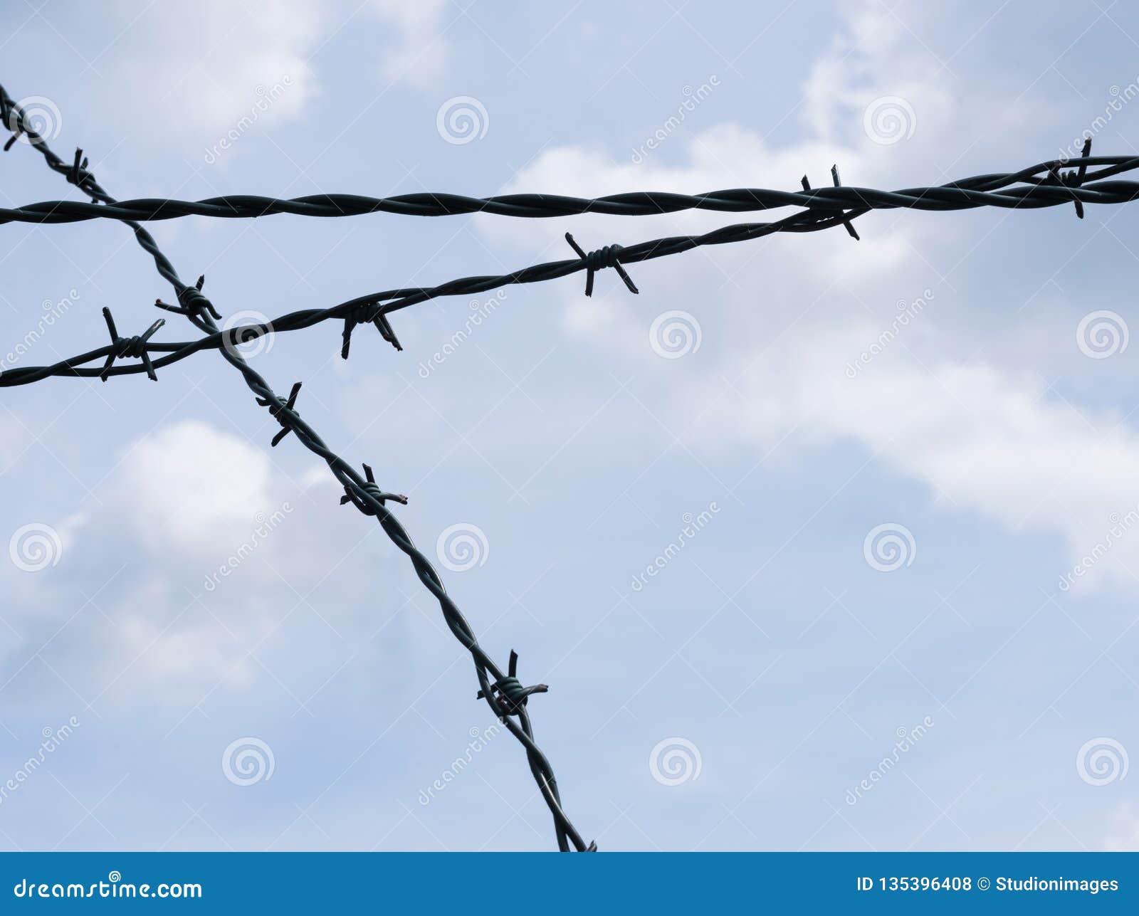 Close-up of Crossed Barbed Wire Against Cloudy Blue Sky - Isolated ...