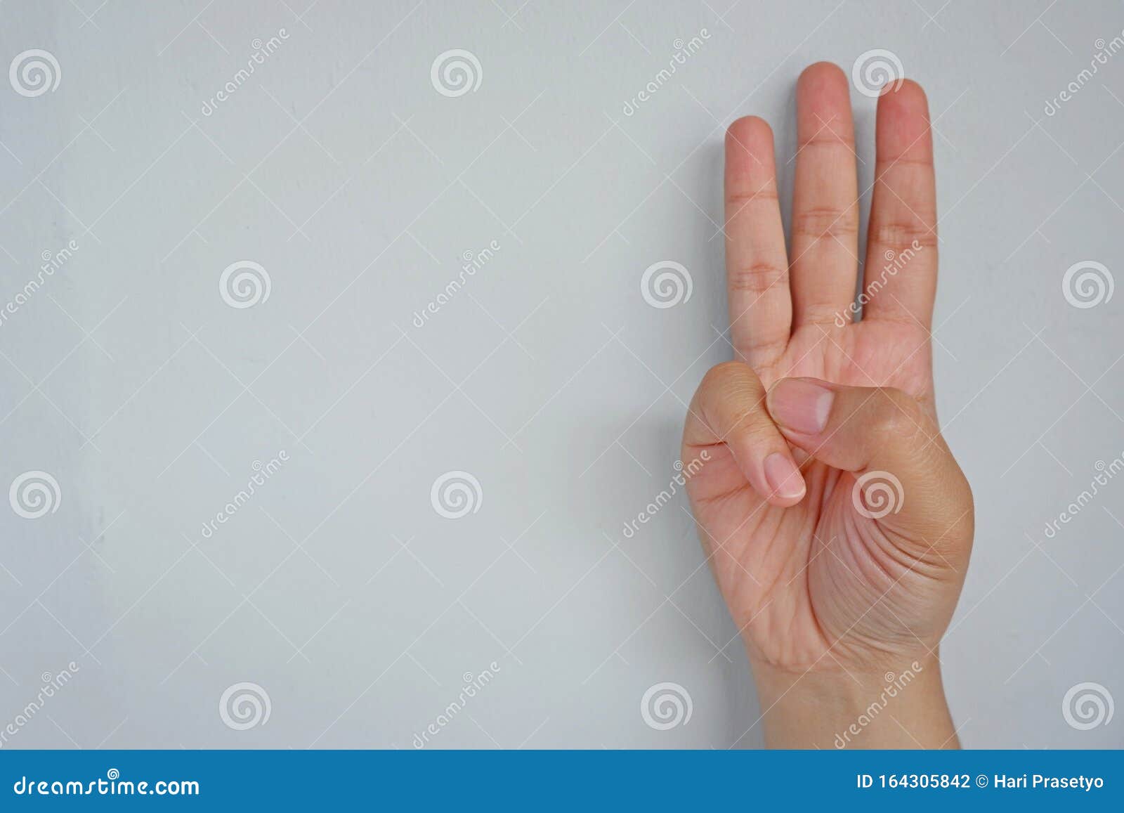 Close-up of Female Hand Showing Three Fingers on Grey Background. Side ... Close-up of Female Hand Showing Three Fingers on Grey Background. Side ...