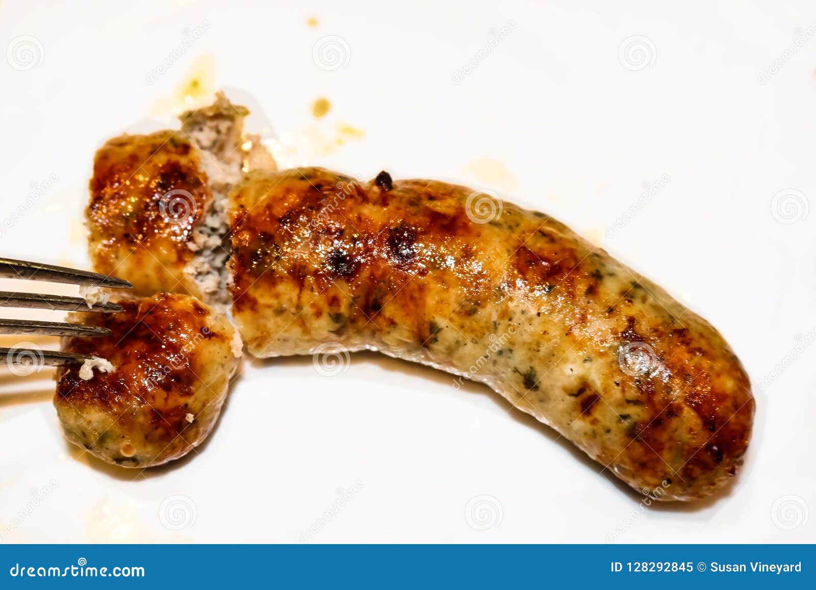 Close-up of Fork Cutting into Delicious Browned Sausage on White ...
