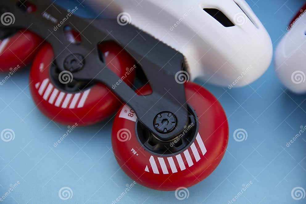 Close-up of the Front Wheel of White Inline Skates on a Blue Background ...