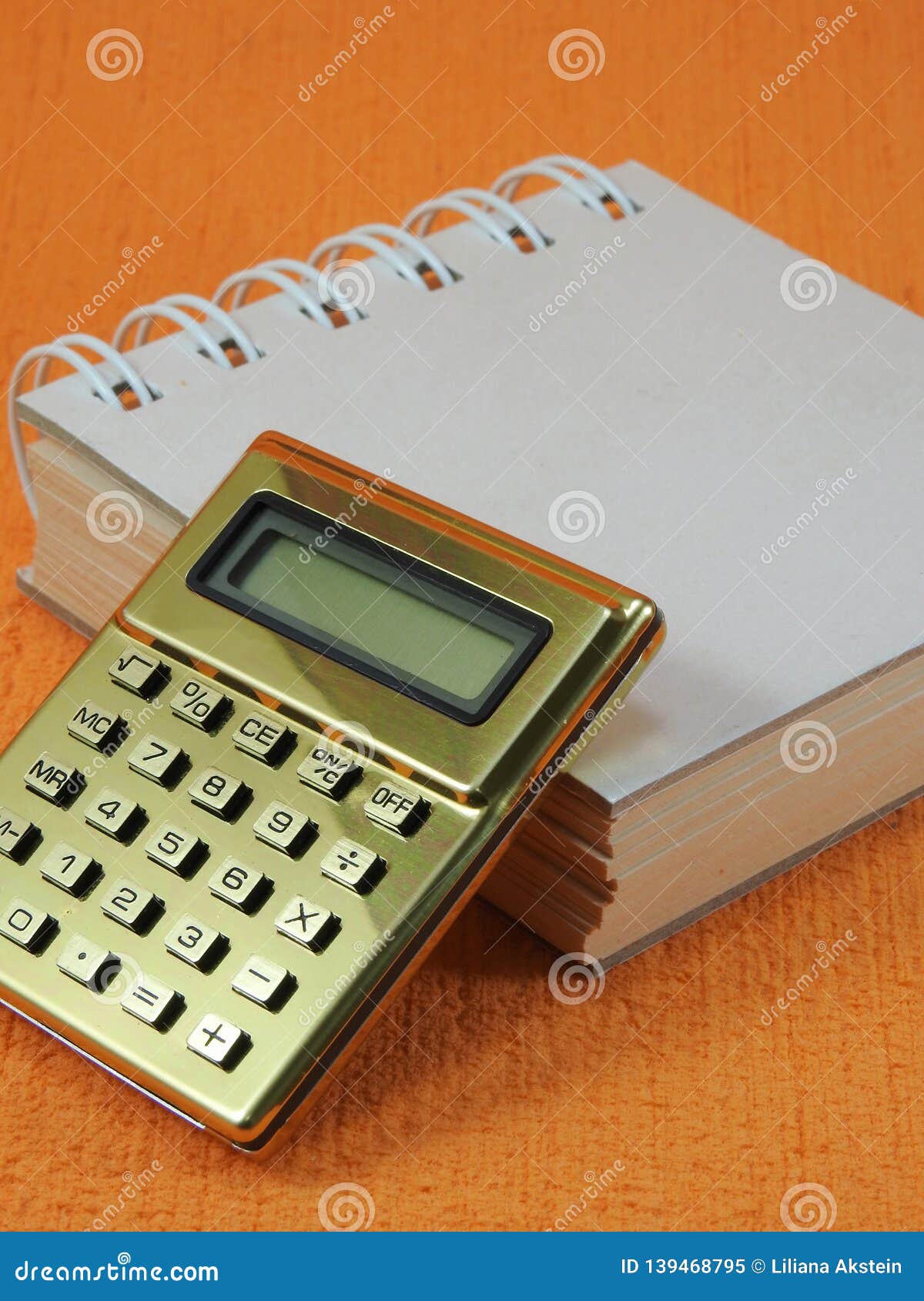 Close-up of a Golden Calculator and a Small Blank Notepad on an Orange ...