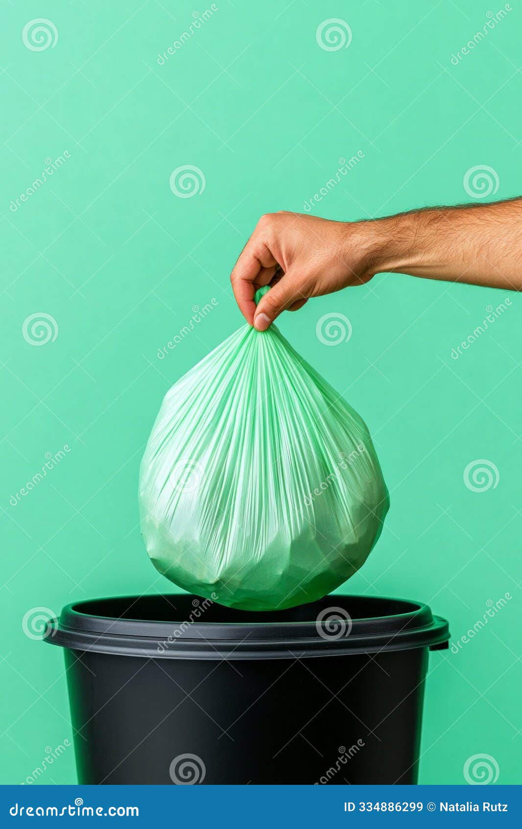 Close-up of a Hand Pulling a Green Garbage Bag from a Black Trash Can ...