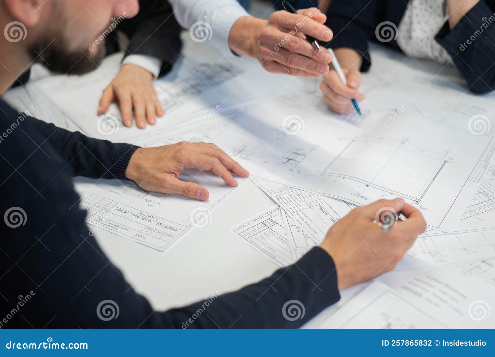 Close-up of the Hands of Four Colleagues with Blueprints on the Table ...