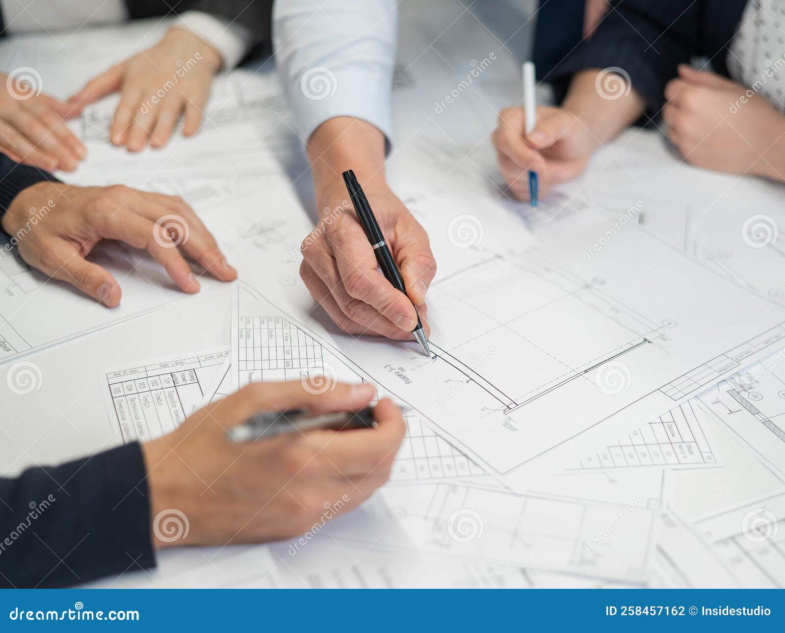 Close-up of the Hands of Four Colleagues with Blueprints on the Table ...