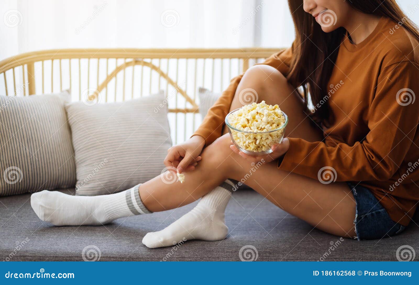 A Beautiful Young Woman Holding And Eating Pop Corn While Sitting On