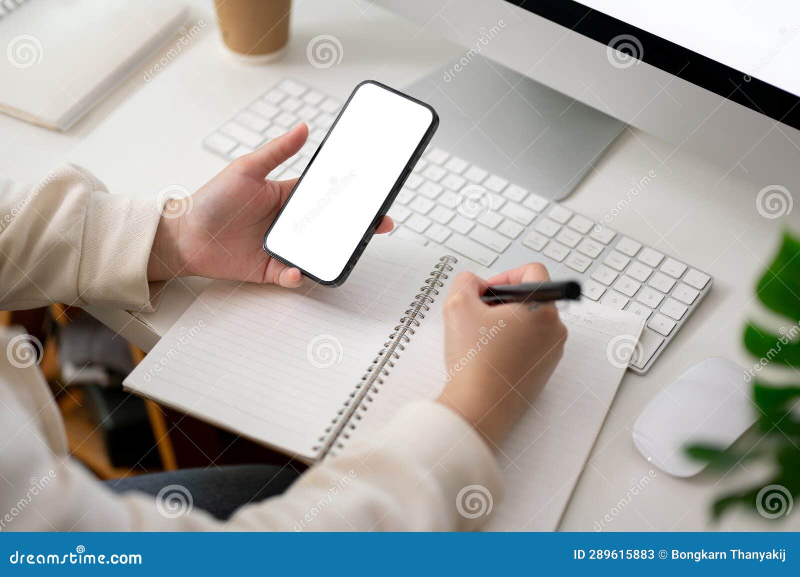 Close-up Image of a Female Using Her Phone and Taking Notes on Her ...