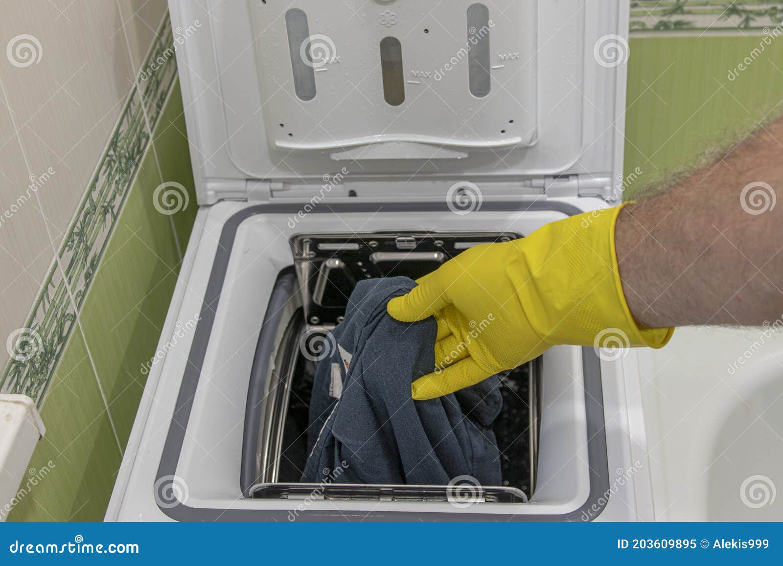 A Man`s Hand is Loading Laundry into a Top-loading Washing Machine for ...
