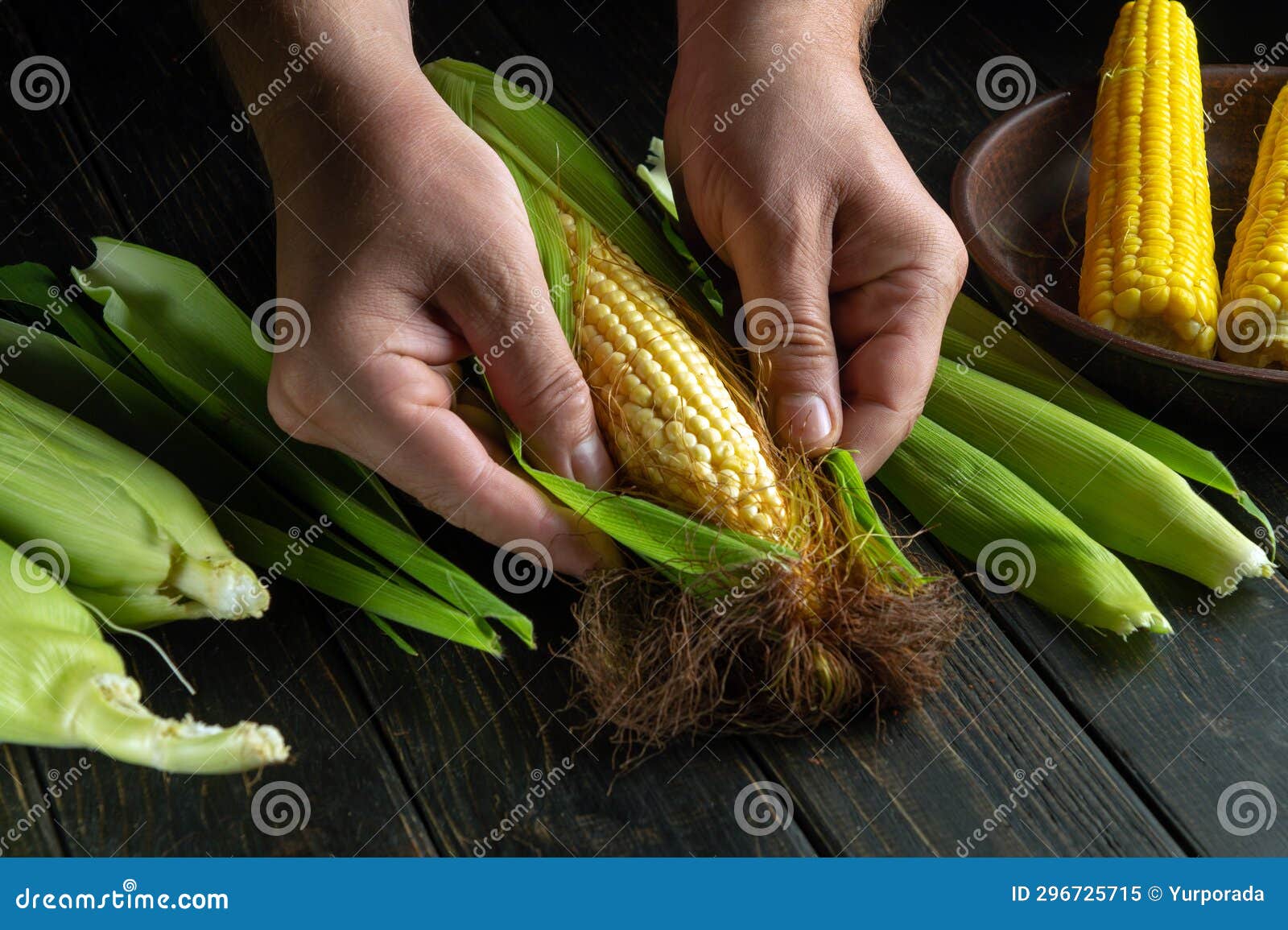 Close-up of a Man Hands Cleaning Corn from Green Husks on the Kitchen ...