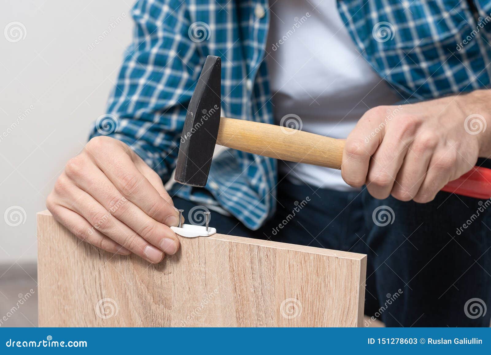 Close-up of Men`s Hands with a Hammer Hammering a Nail into the Leg of ...