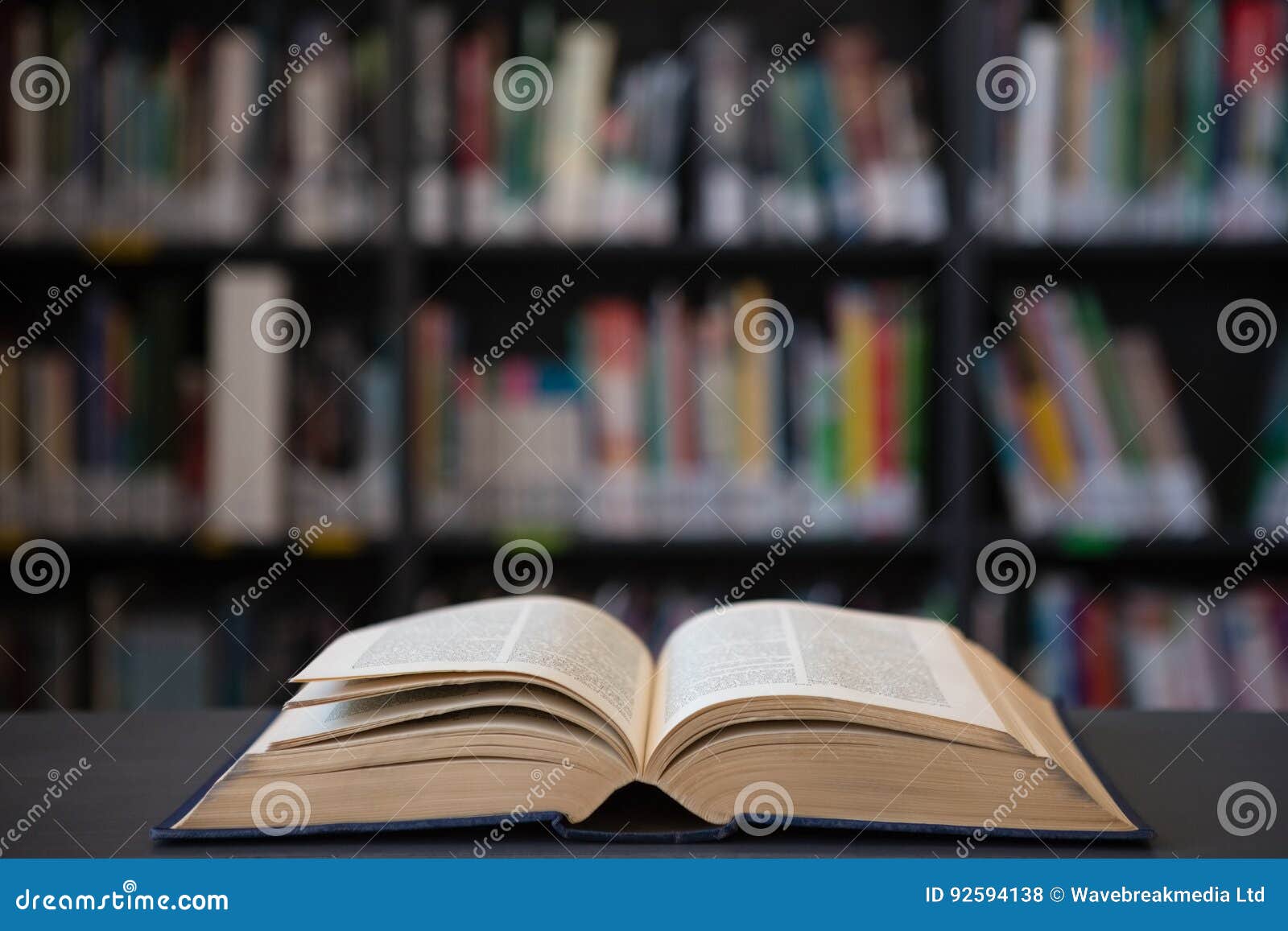 Close Up of Open Book on Table Against Shelf Stock Photo - Image of ...