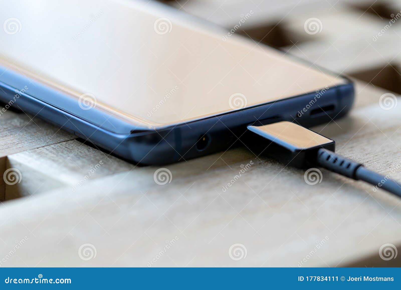 A Close Up Portrait of a Smartphone with a USB Cable in Its Port. it is ...