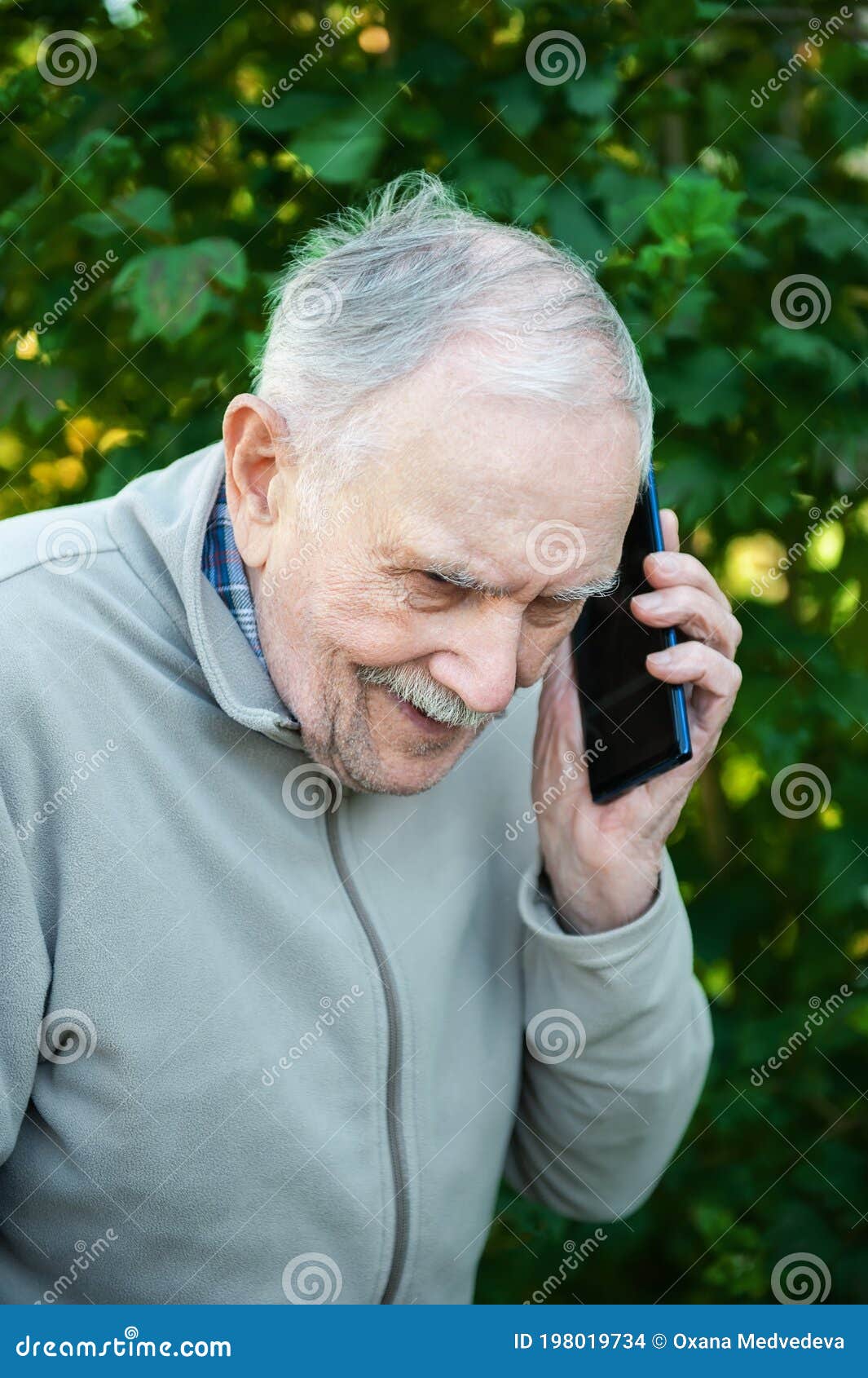 Close-up Portrait of a Smiling Elderly Man Using a Mobile Phone. Active ...