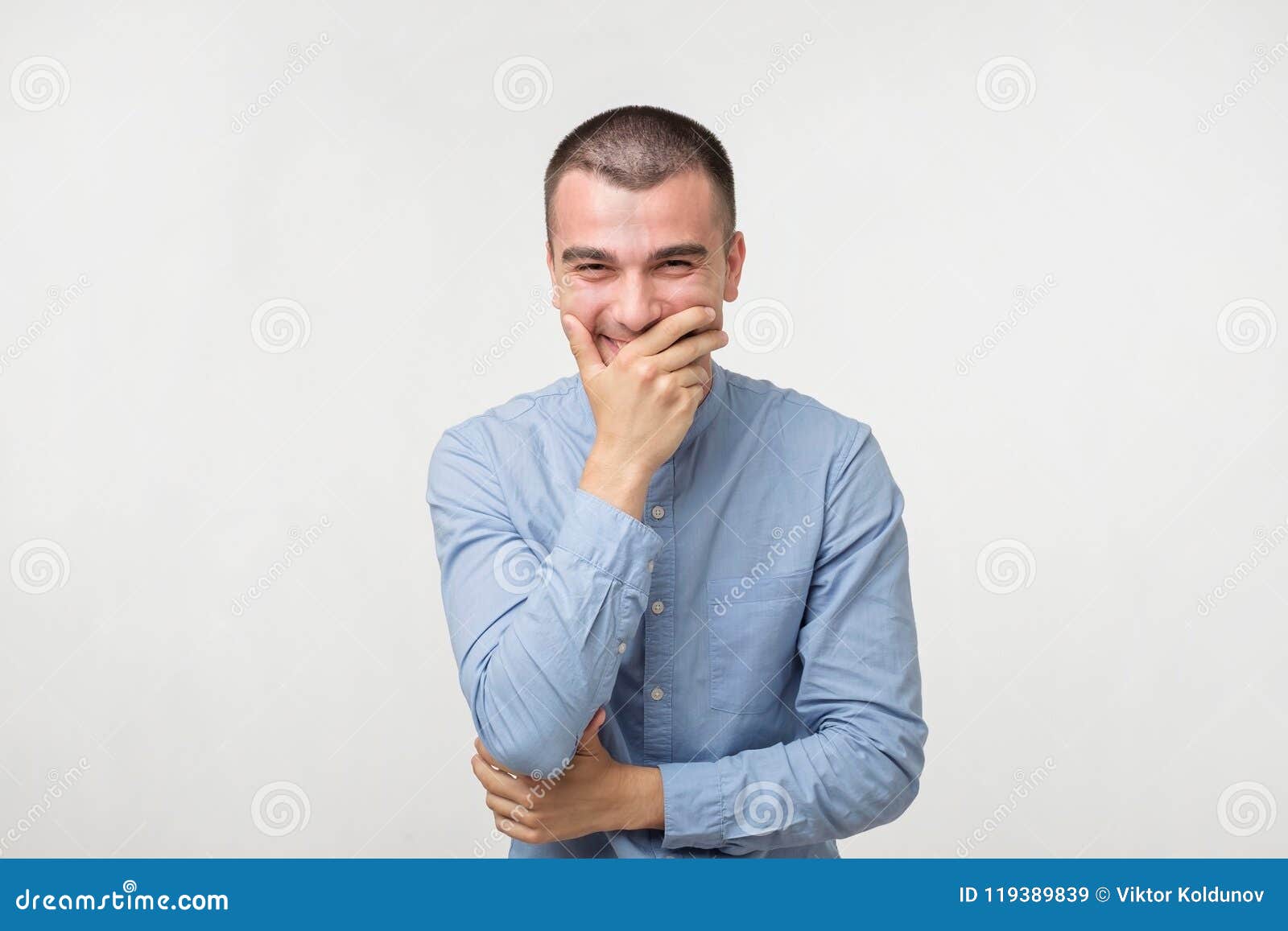 Close Up Portrait Of Young Man Laughing And Covering His Mouth With