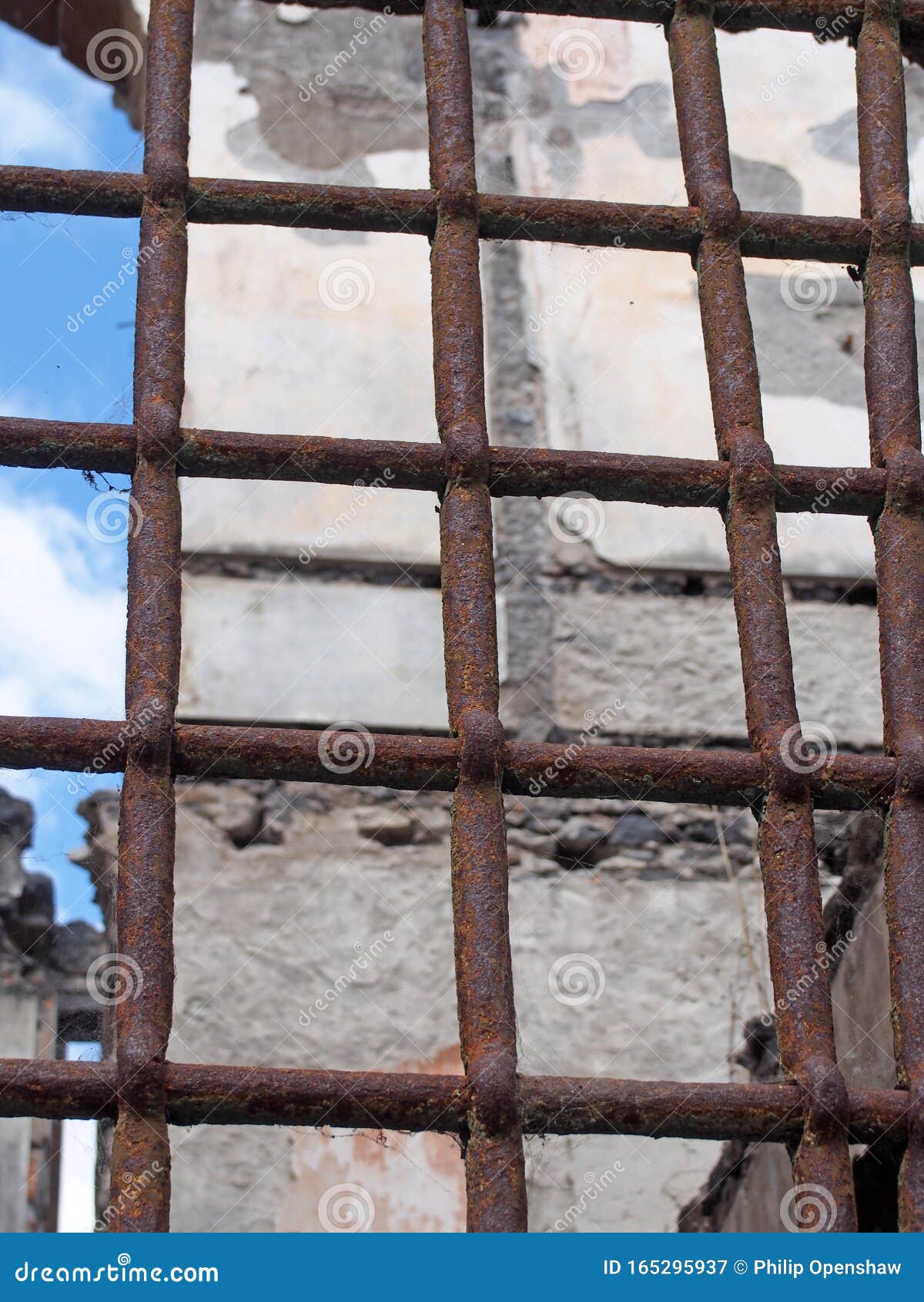 Close Up of a Rusting Iron Fence with Bars in Front of a Ruined ...