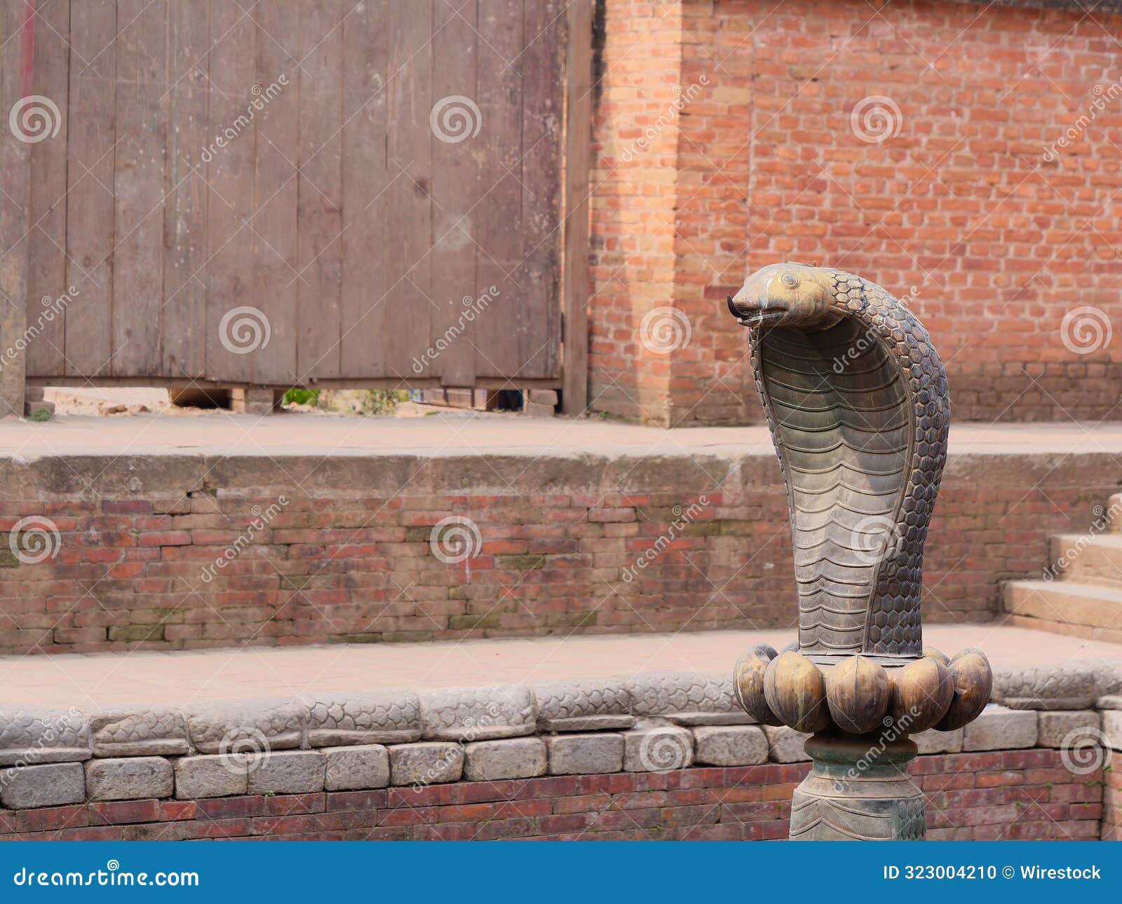 A Close-up of a Snake Statue in Front of a Rustic Brick Wall and Wooden ...