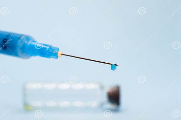 A Close-up Syringe Needle with a Drop of Solution at the End Against an ...