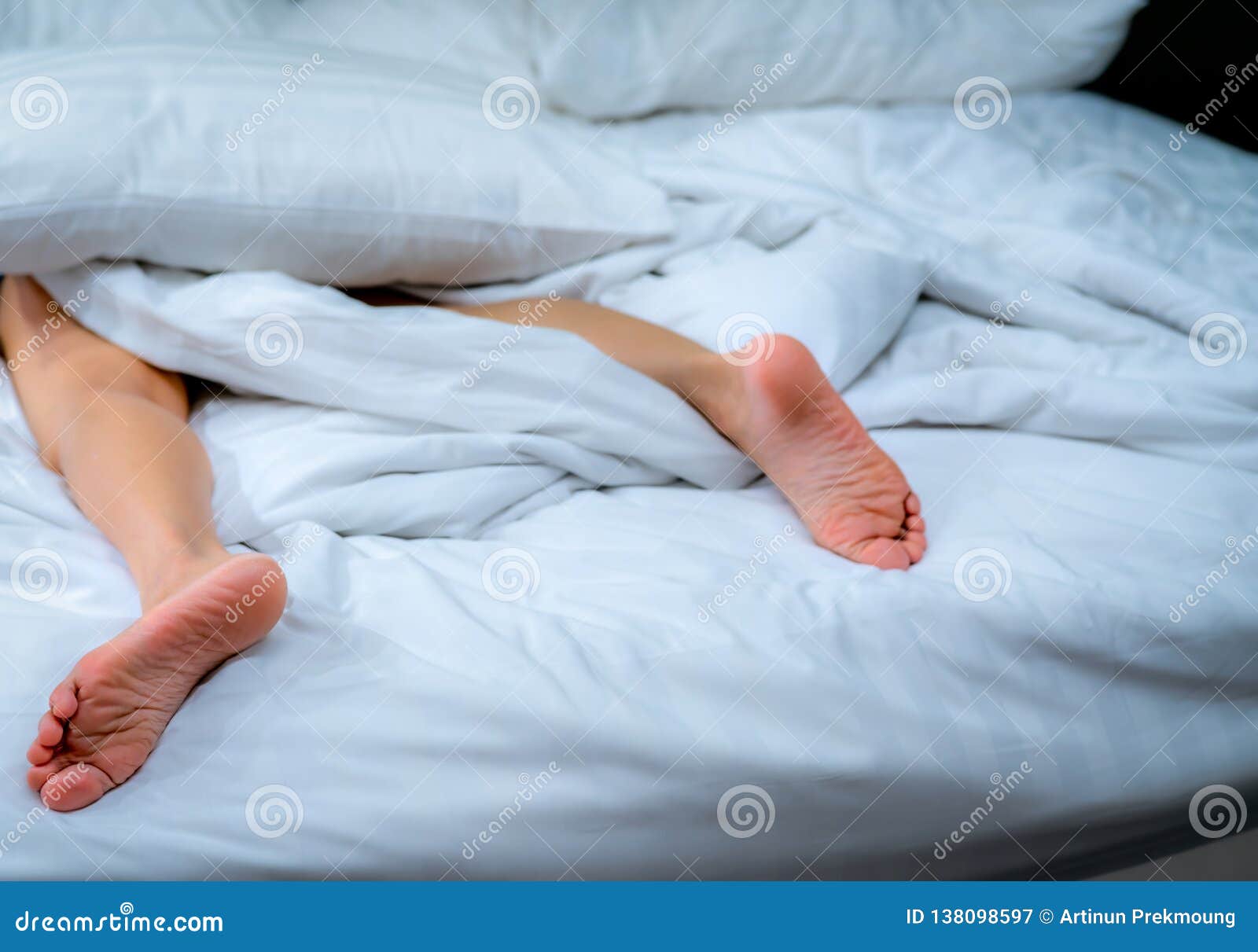 Close Up Woman Bare Feet On The Bed Over White Blanket And Bed Sheet In