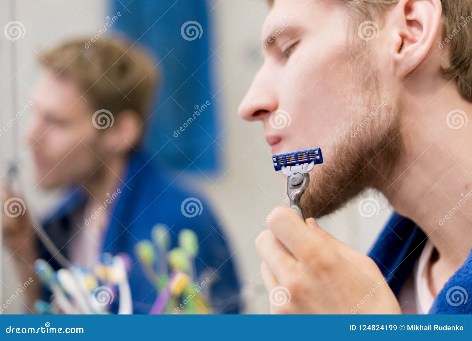 Close Up Young Bearded Man Using Razor To Shave Beard in the Morning in ...