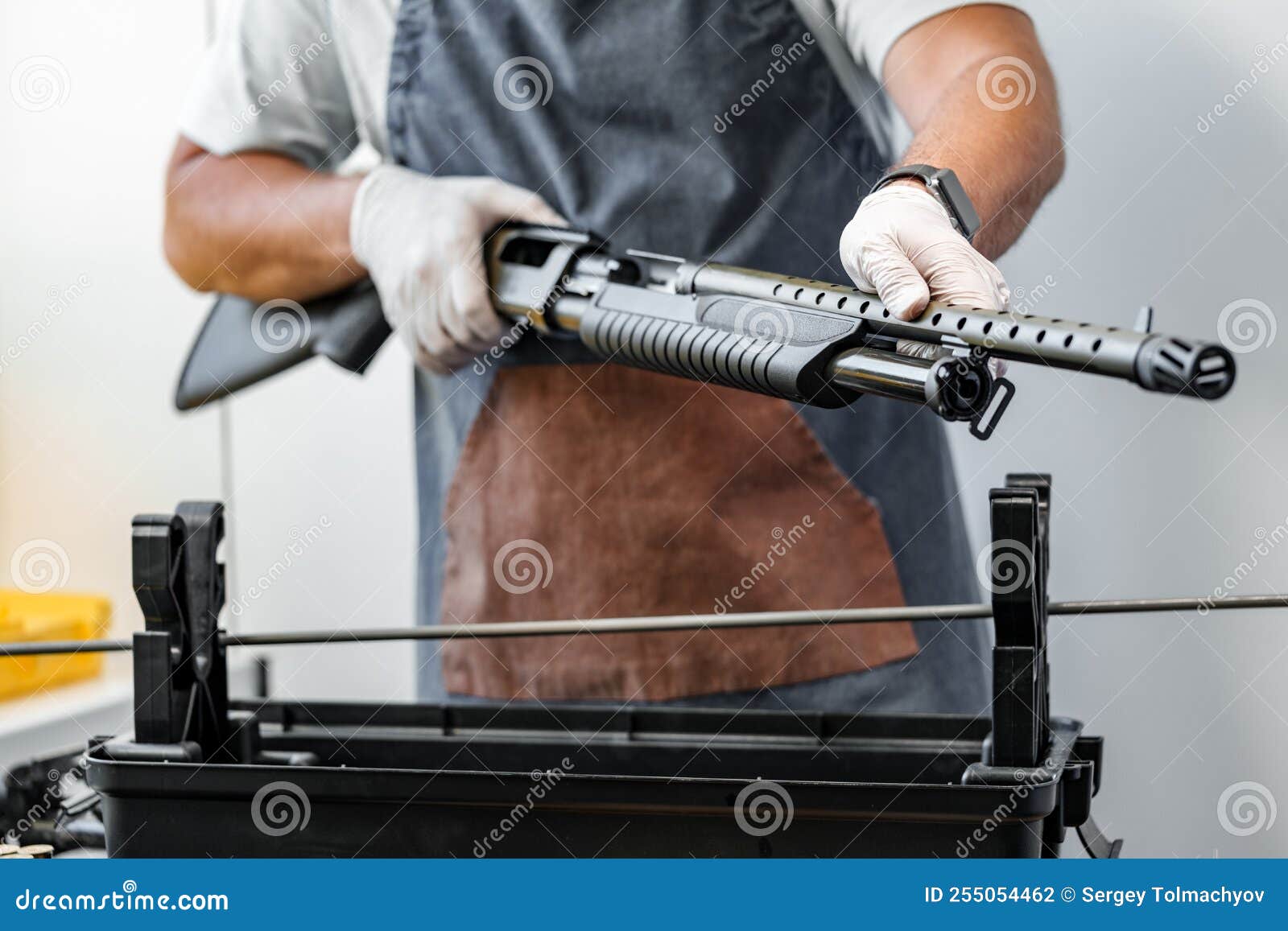 Close Up of Young Man in Apron Disassembling a Gun Above the Table ...