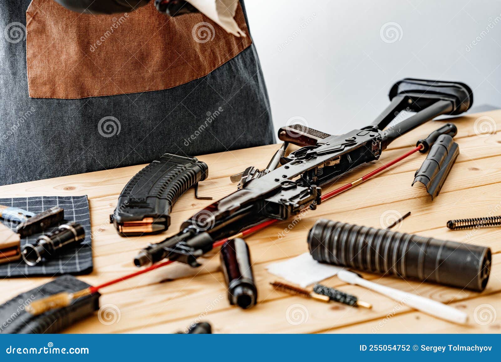 Close Up of Young Man in Apron Disassembling a Gun Above the Table ...