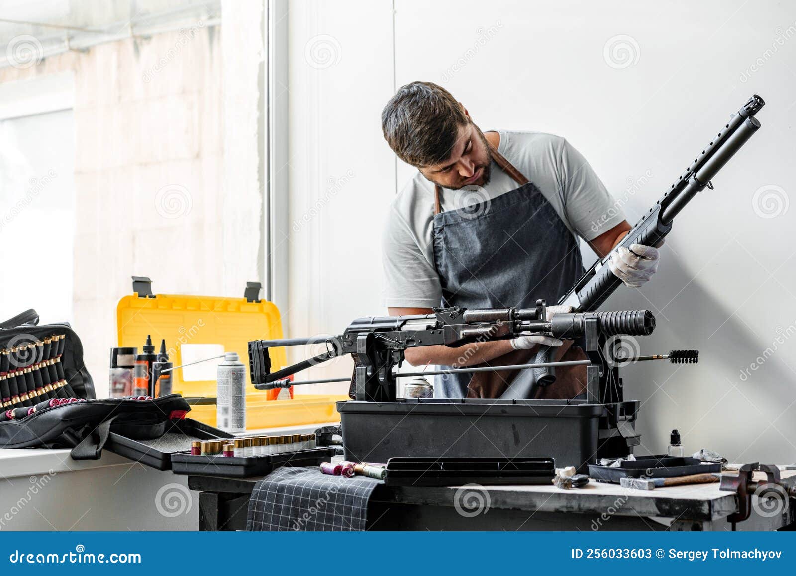 Close Up of Young Man in Apron Disassembling a Gun Above the Table ...