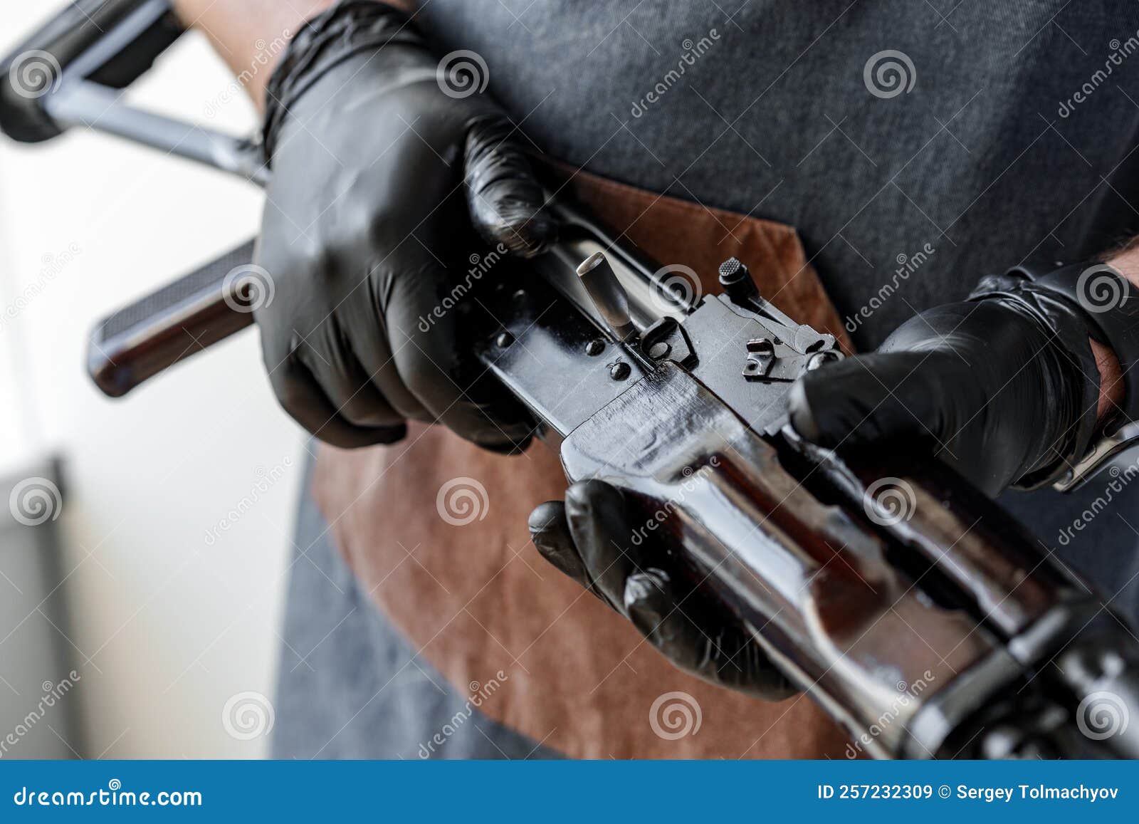 Close Up of Young Man in Apron Disassembling a Gun Above the Table ...
