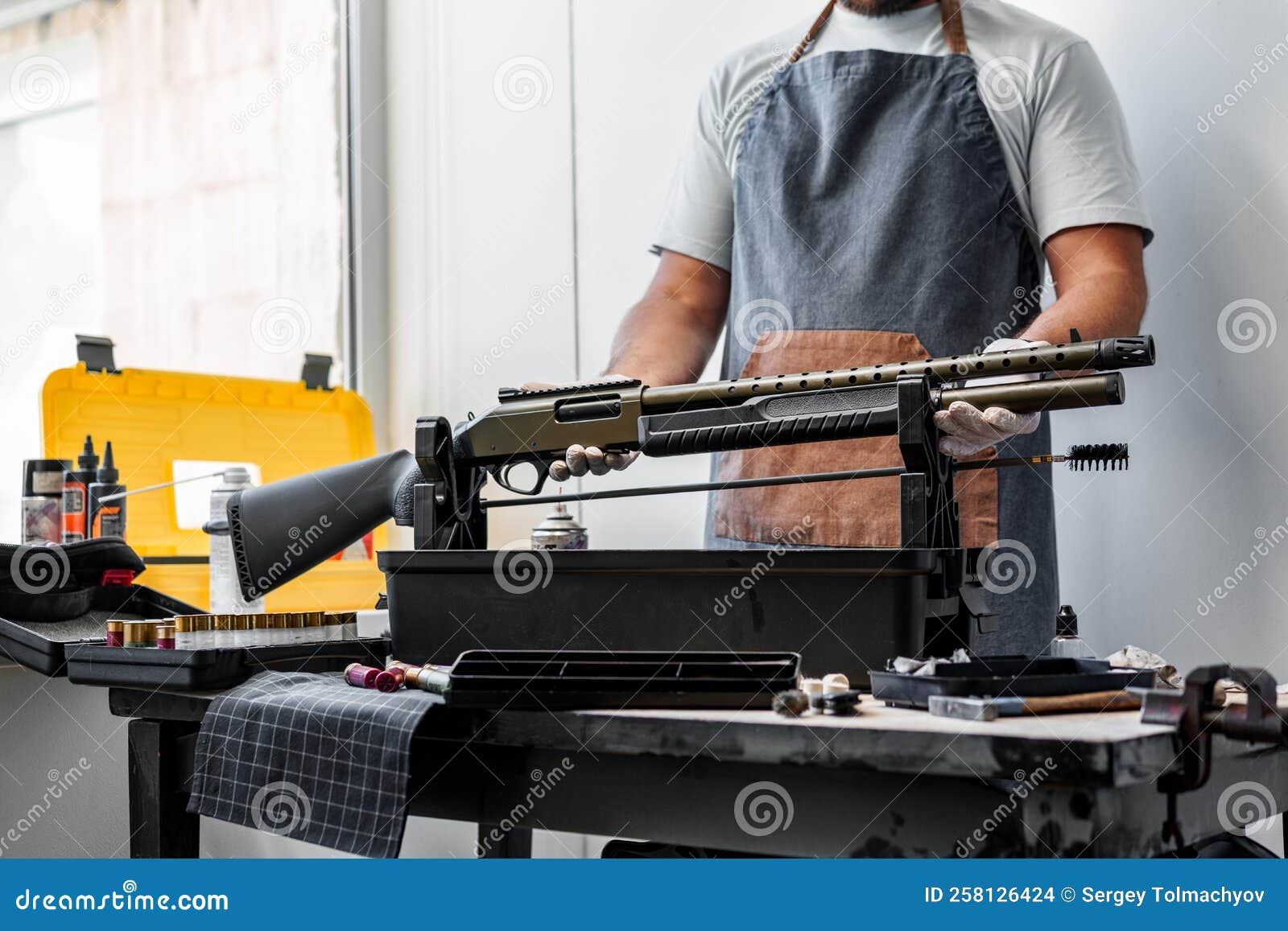 Close Up of Young Man in Apron Disassembling a Gun Above the Table ...