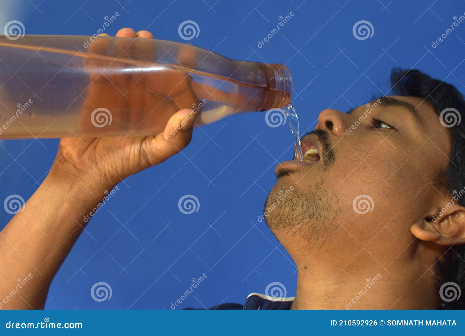 Close Up of Young Man Drinking Water from Bottle on Blue Background ...