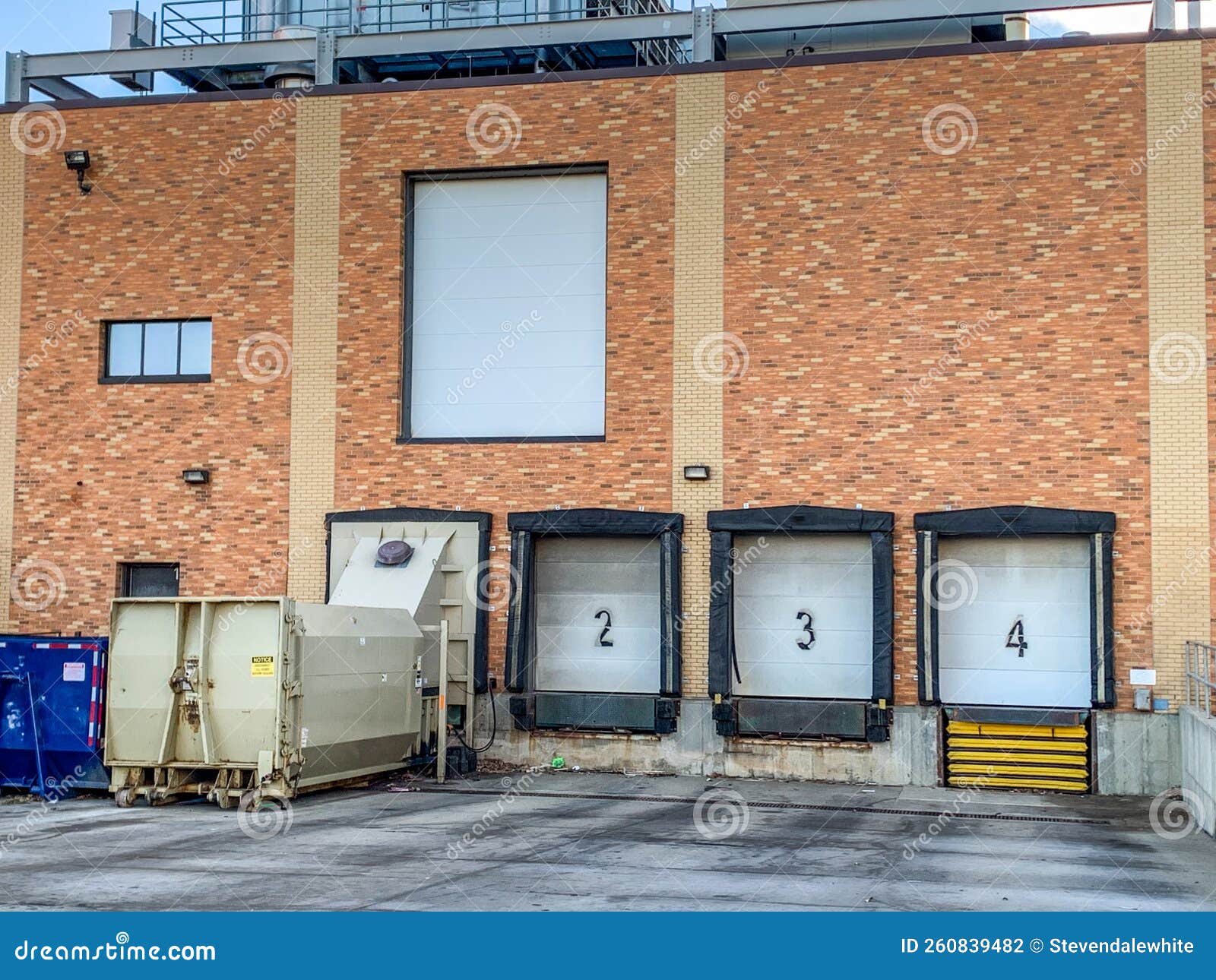 Closed Bay Doors and Garbage Roll-offs Outside an Industrial Complex ...