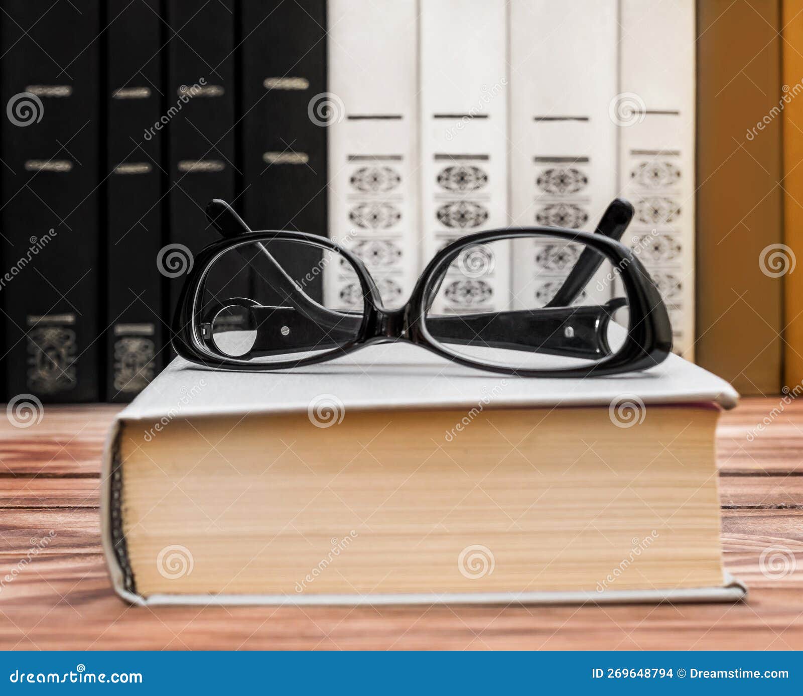 Closed Book with Eyesglasses on the Table at the Library Stock Photo ...