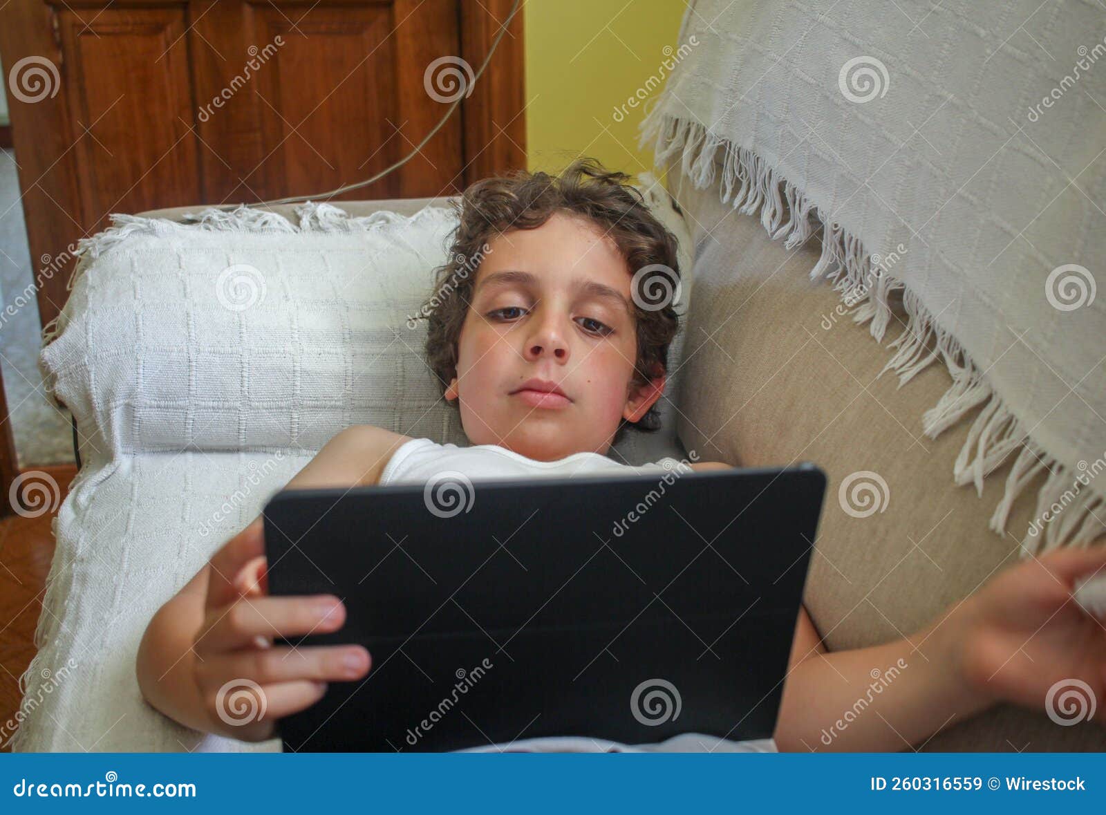 Closeup of a Boy Looking at the Tablet while Lying on the Couch Stock ...