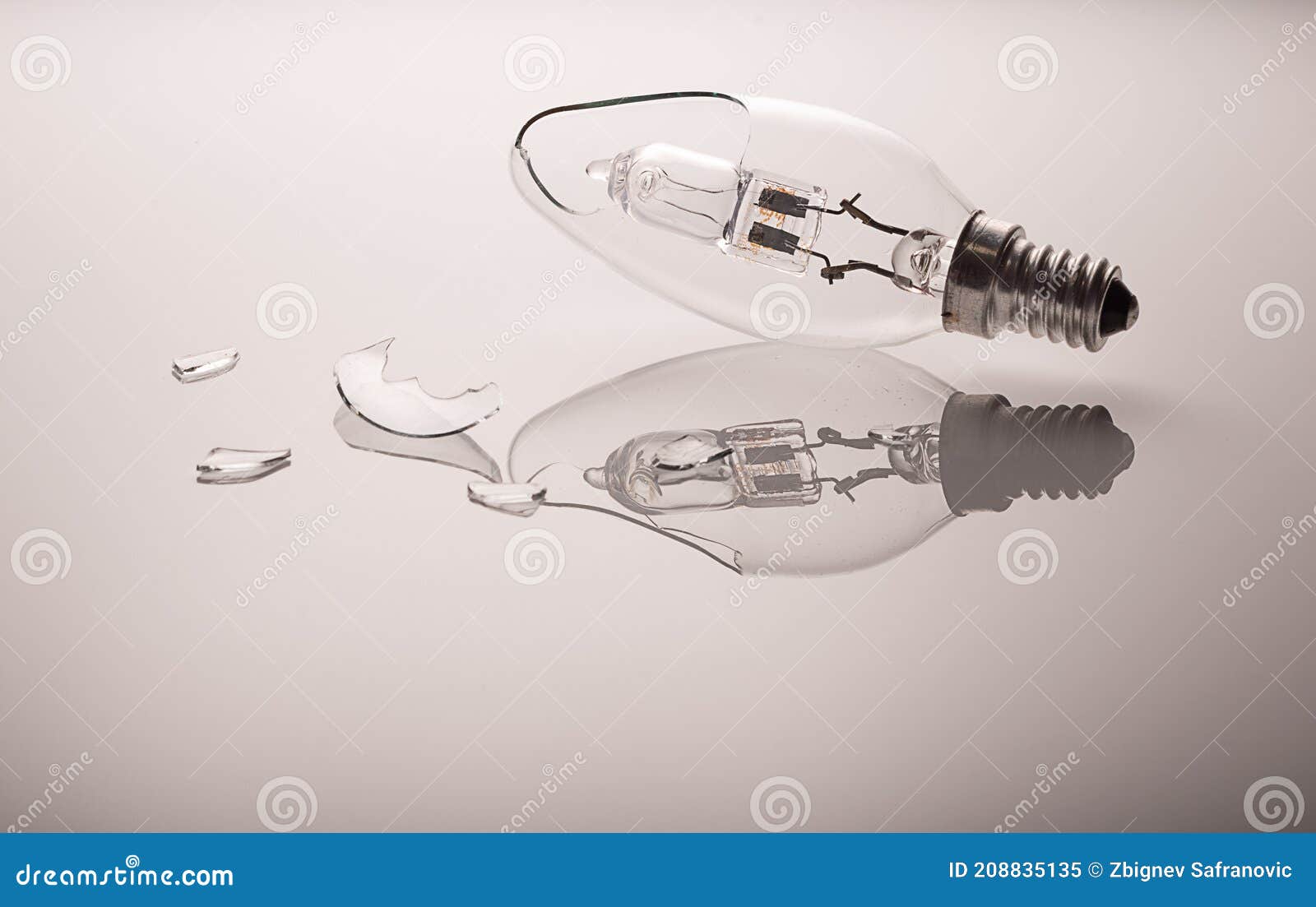 Closeup Broken Light Bulb with Reflection and Glass Pieces Next To it ...