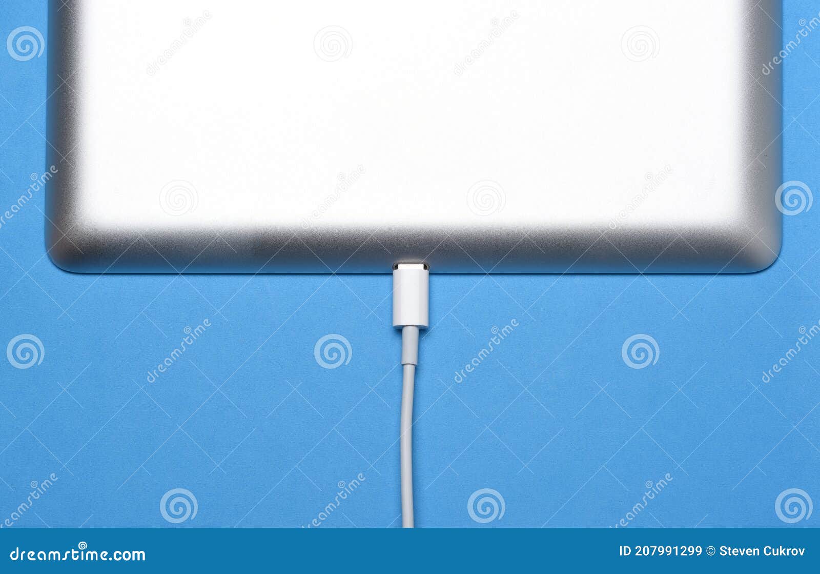 Closeup of a Charging Cord and Tablet Computer on a Blue Background ...